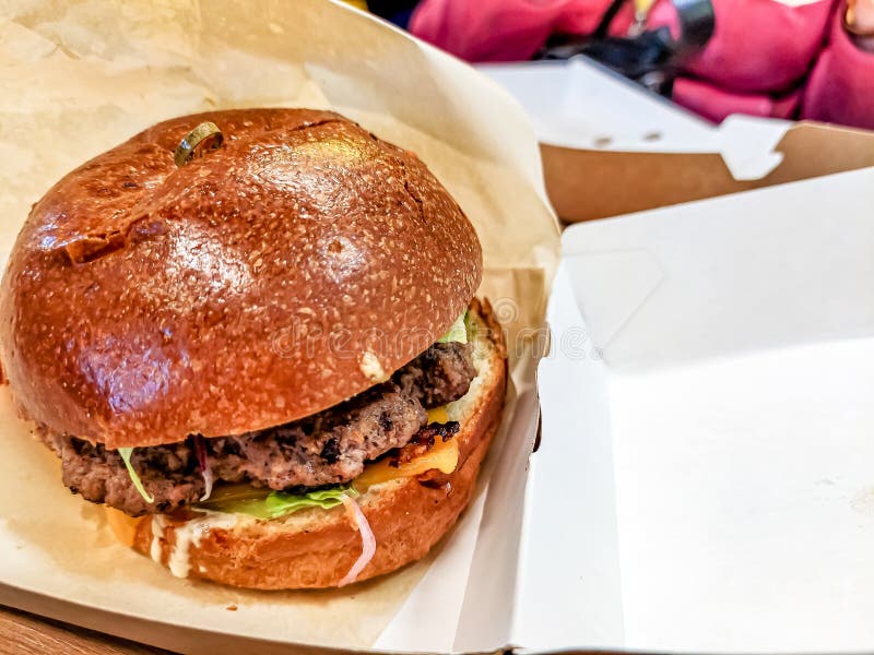 A Hamburger with a Burger, Vegetables and Tomatoes is on Paper in a ...