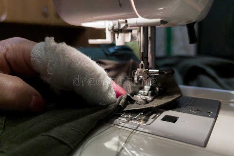 A Hand of Aged Womans with a Bandaged Finger Sews with a Sewing Machine ...