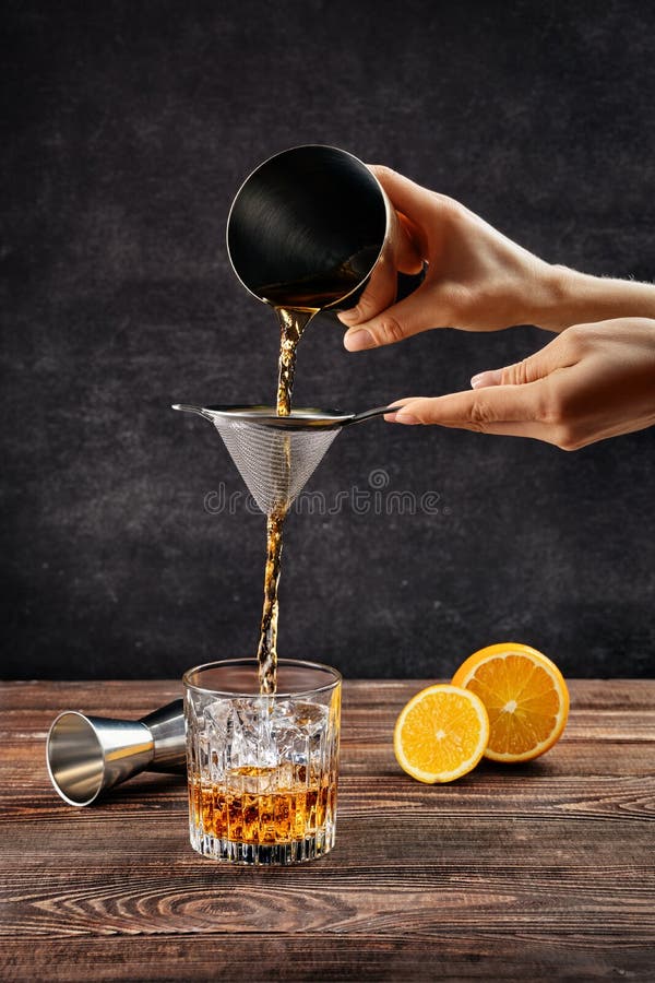 Hand of Bartender with Shaker and Strainer Pouring Cocktail with Brandy ...