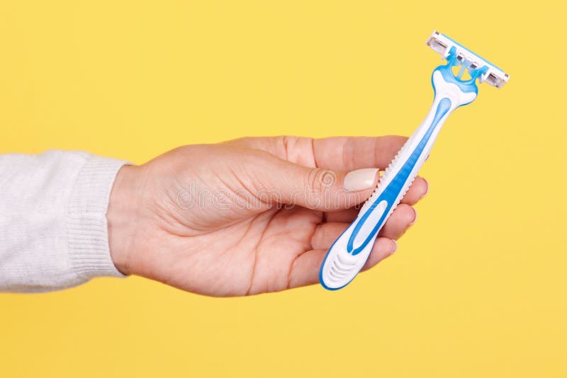 Hand with Blue Disposable Razor. Isolated on Yellow Background Stock ...
