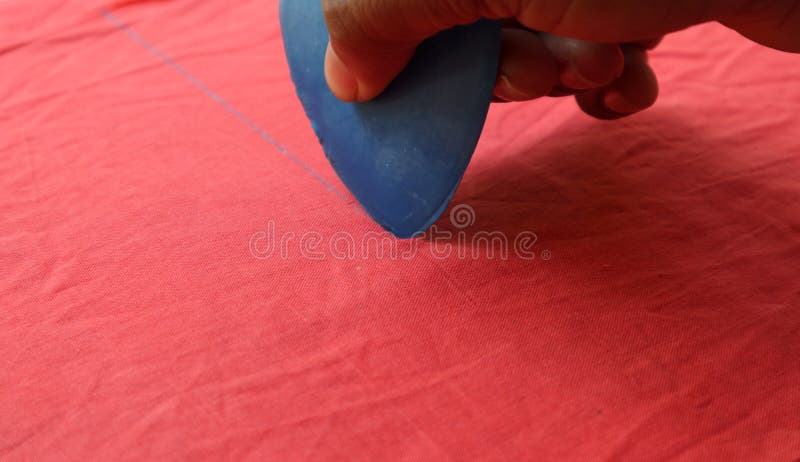 A Hand with Blue Triangle Tailor Chalk To Draw Marking on a Red Cloth ...