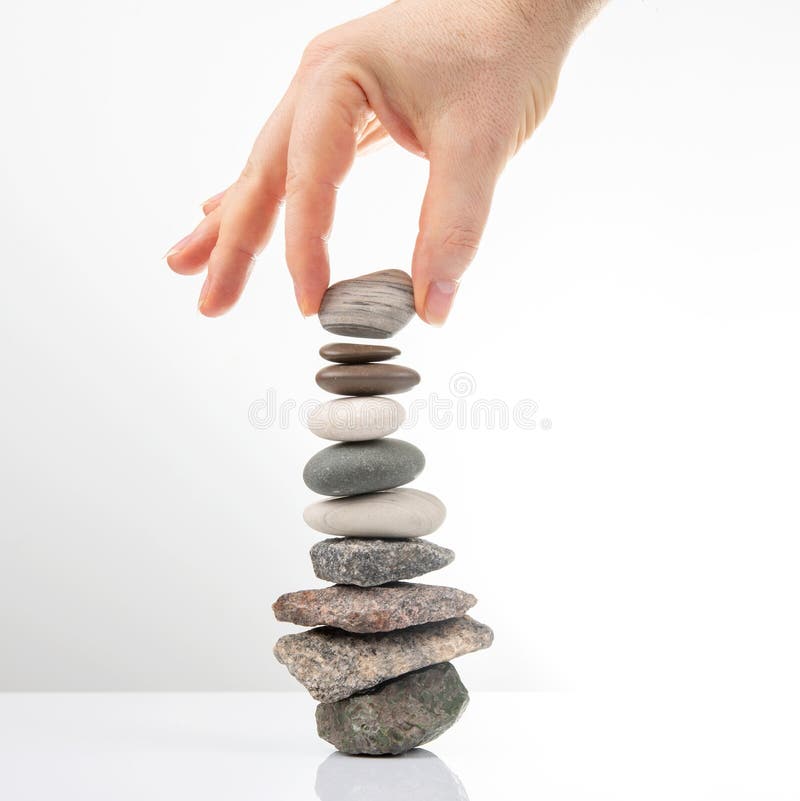 Hand Builds a Pyramid from Stacked Stones on a White Background ...