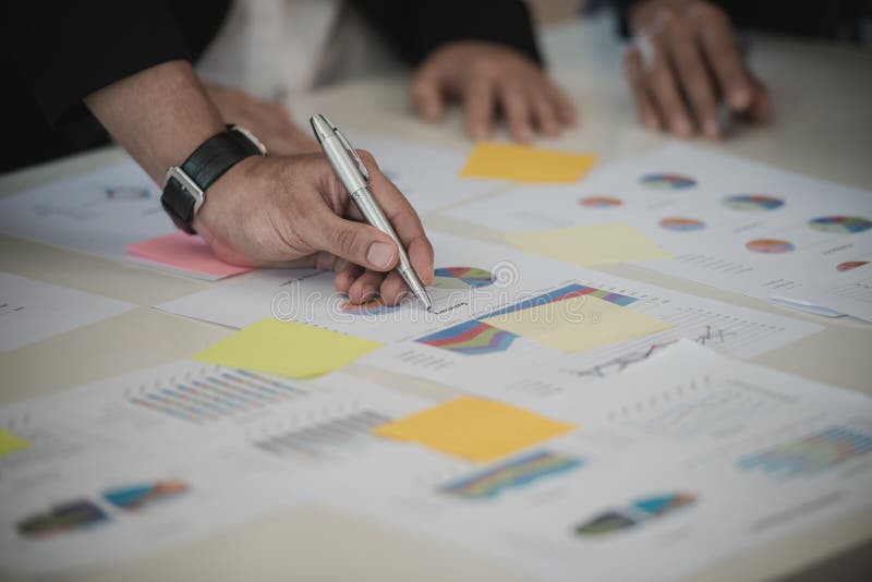 Hand of Businessman Working Write with a Pen on Data Charts,document at ...
