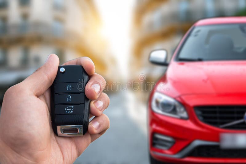 Hand with a Car Key in Foreground and Beatiful Red Luxurious Red Car in ...