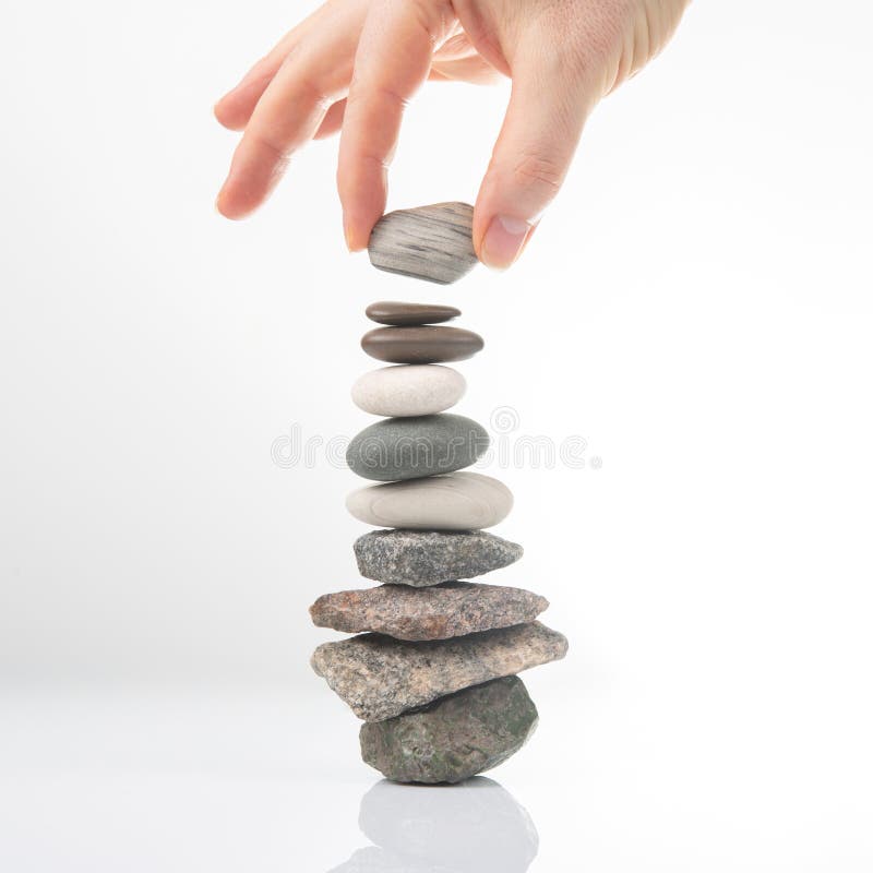 A Hand Carefully Places a Stone on a Balanced Stack of Smooth Pebbles ...