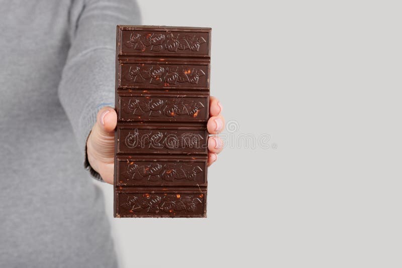 Hand with Chocolate Bar with Nuts on Grey Background Stock Photo ...