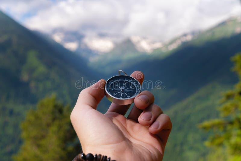 A Hand with a Compass Against the Backdrop of Epic Snow-capped ...