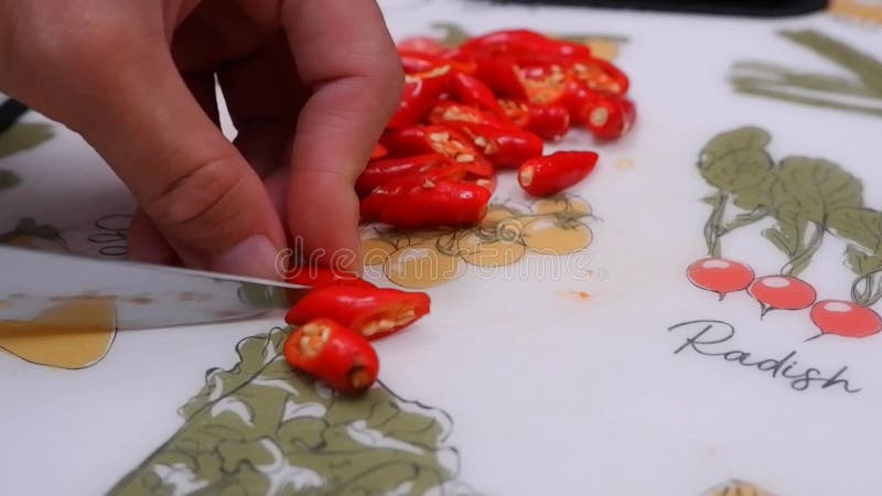 Hand Cutting Red Pepper with Sharp Knife Onto Cutting Board into Pile ...