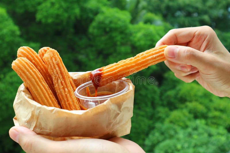Hand Dipping a Churro in Dolce De Leche Caramel Sauce Stock Photo ...
