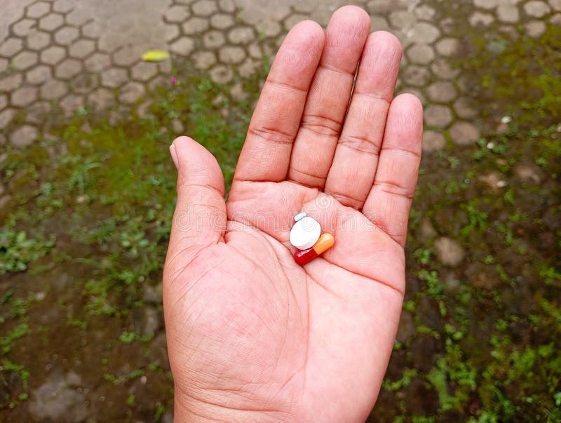 Hand Displays a Small Collection of Medication: a White Tablet, a Red ...
