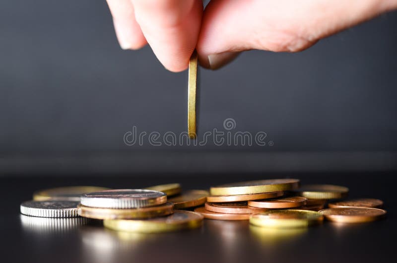 Hand Drops a Coin into a Stack of Coins on a Black Background Stock ...