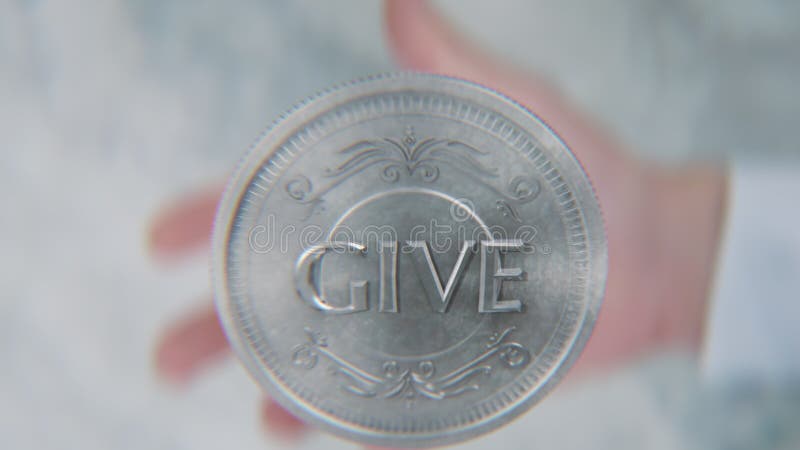A Hand Flips a Coin Marked Take and Give, Spinning Toward the Camera in ...