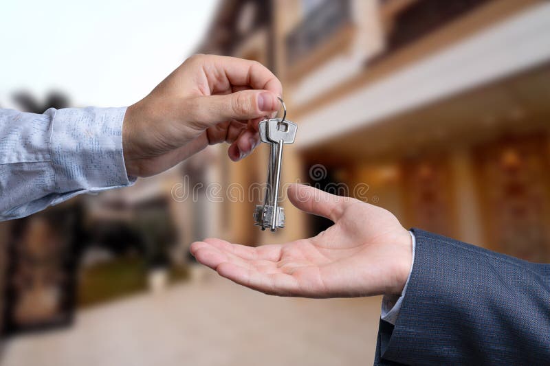 A Hand Giving a Key To Another Hand. House in the Background. Stock ...