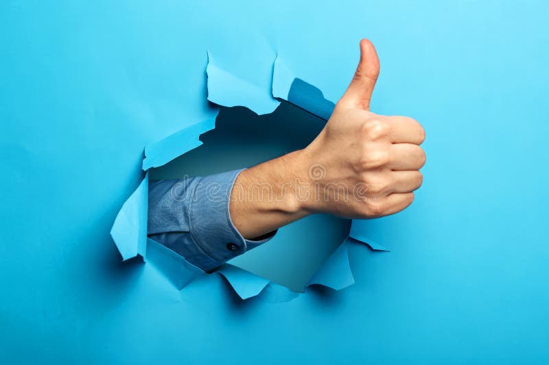 Hand Giving Thumbs Up Gesture through Torn Blue Paper Background in ...