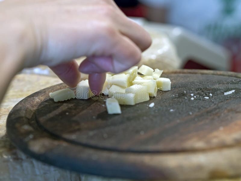 Hand Grasping Cubes of Cheese on a Wooden Cutting Board Stock Image ...