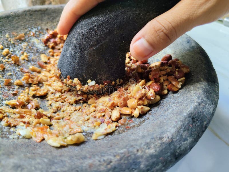 A Hand is Grinding Fried Peanuts in a Stone Mortar Stock Photo - Image ...