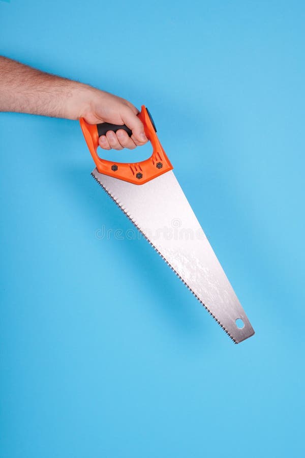 Hand with Handsaw, Carpentry and Construction Tool. Isolated on Blue ...