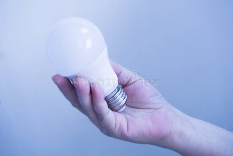 Hand Hold LED Light Bulb on Blue Background Defocus. Stock Image ...