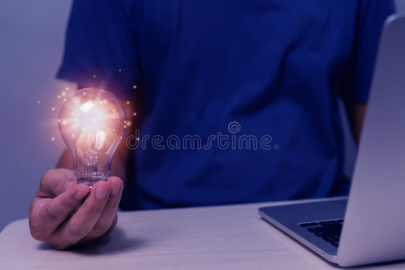 Hand Hold Light Bulb and Computer on Desk.Business Innovation ...