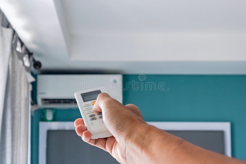 Hand Holding AC Remote Control Directed on the Air Conditioner Inside ...