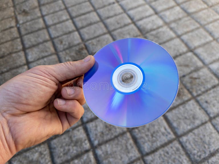 A Hand Holding a Blue Disc in Front of a Brick Sidewalk Stock Image ...