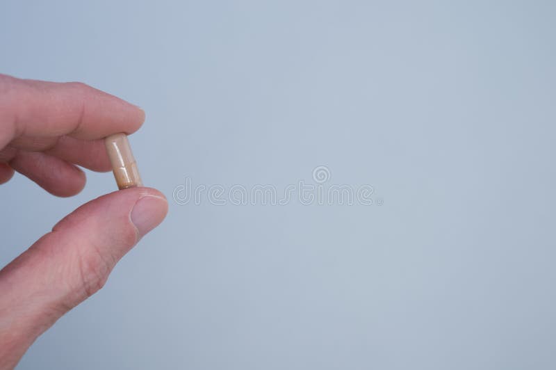 Hand Holding a Capsule on Gray Background with a Copy Space Stock Photo ...