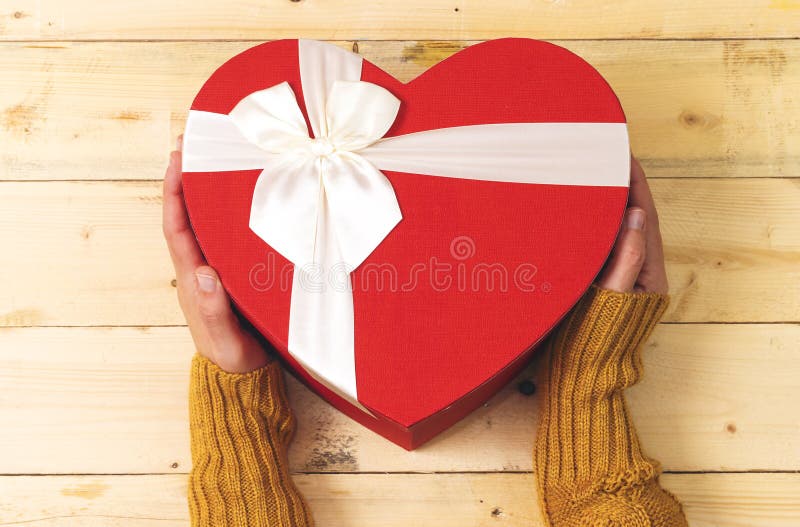 Hand Holding Closed Heart Shaped Box on Wood Table. Stock Photo - Image ...