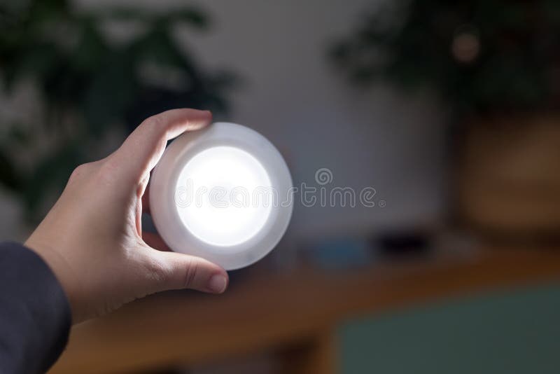 Hand Holding a Compact LED Light in a Dimly Lit Room among Smooth ...