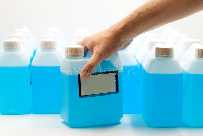 Hand Holding a Container of Blue Ethyl Alcohol among Multiple Liquid ...
