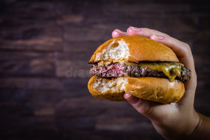Hand Holding a Craft Beef Burger with Cheese on Rustic Background Stock ...