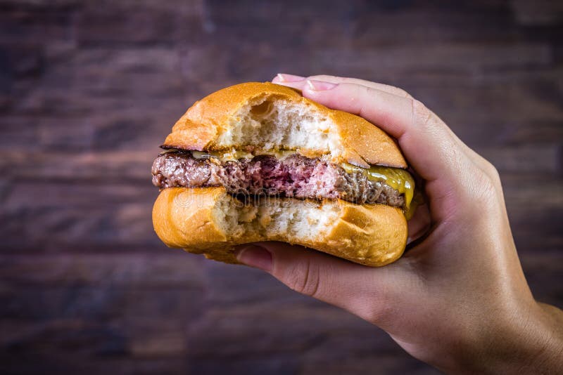 Hand Holding a Craft Beef Burger with Cheese on Rustic Background Stock ...