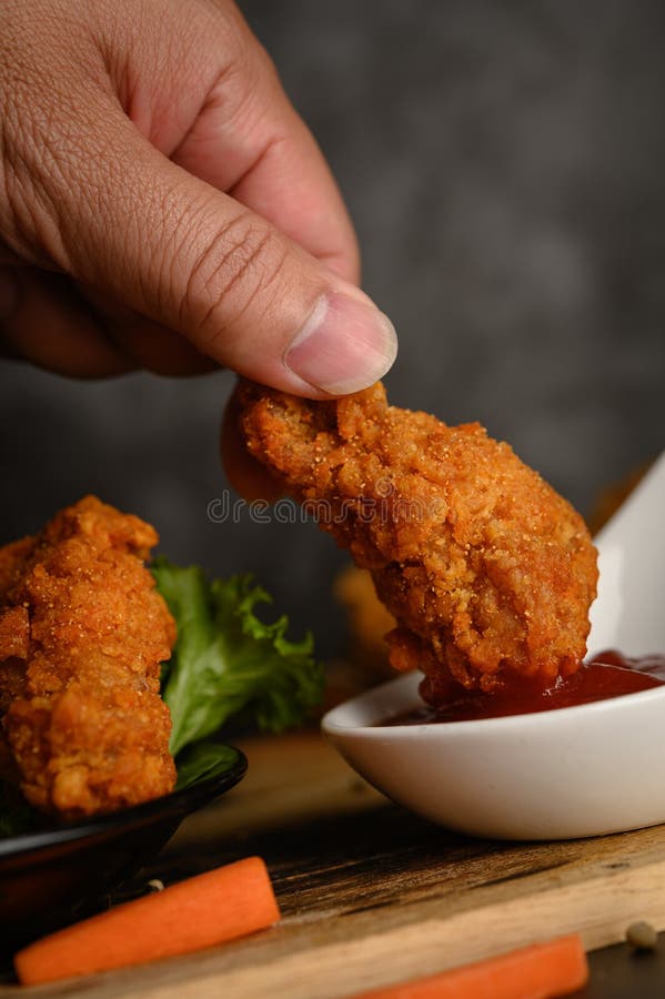 Hand Holding Crispy Fried Chicken Dipped in Tomato Sauce Stock Photo ...