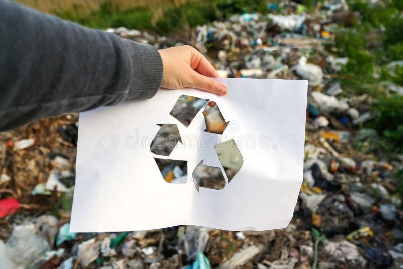 Hand Holding Cut Paper with the Logo of Recycling on Dump Garbage Trash ...