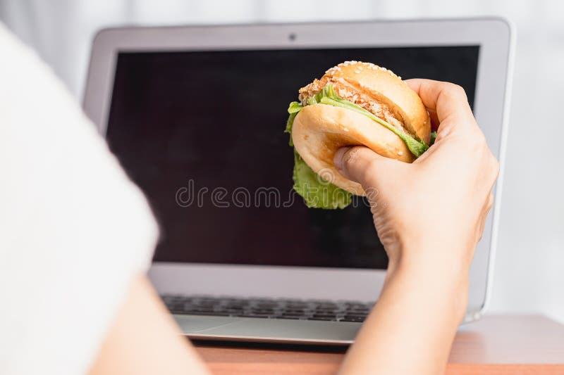 Hand Holding a Delicious Hamburger and Using Laptop Computer Stock ...