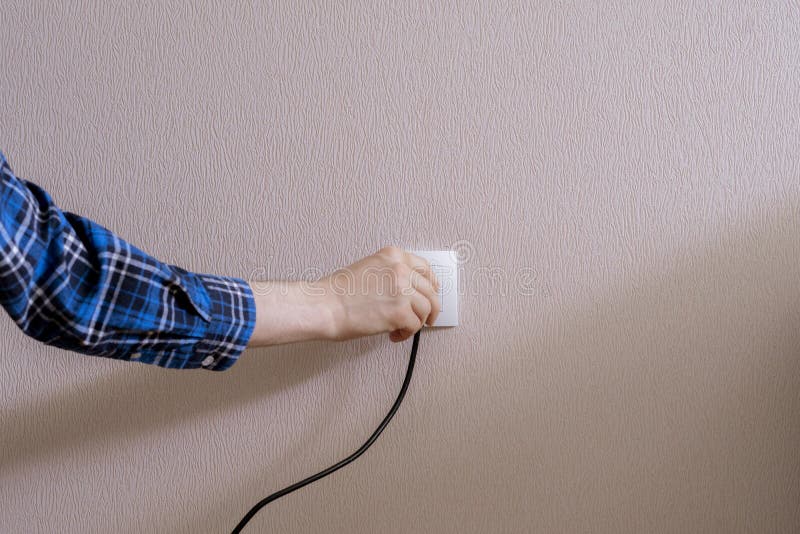 A Hand Holding the Electricity Power Cable and Insert it in the Socket ...