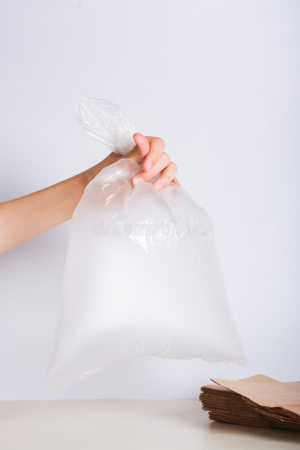 Hand Holding an Empty Transparent Plastic Bag and a Stack of Eco ...