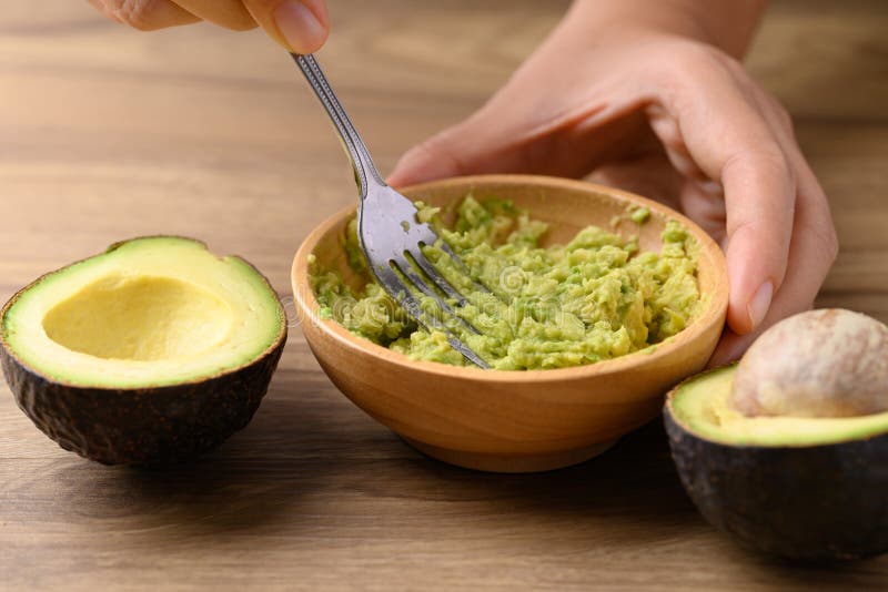Hand Holding Fork and Smashing Avocado in Wooden Bowl Stock Photo ...