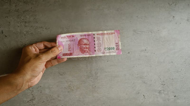 Hand Holding Indian 2000 Rupee Note Against a Concrete Background Stock ...