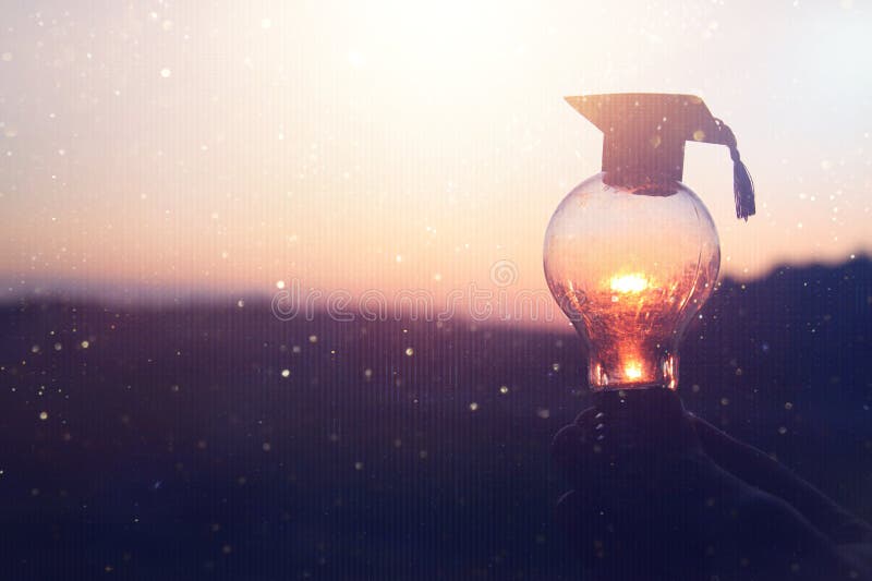 A Hand Holding a Light Bulb and Graduation Cap in Front of the Sun ...