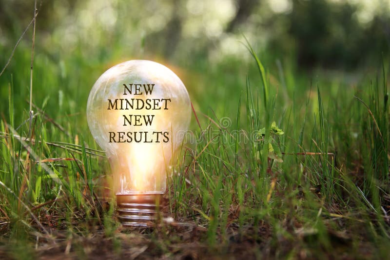 Hand Holding Light Bulb with the Text New Mindset on the Green Grass ...