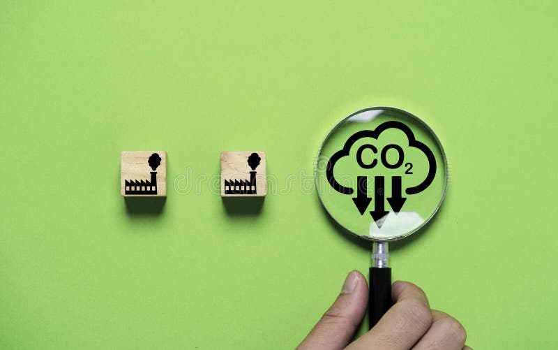 Hand Holding Magnifier Glass with CO2 Reducing Icon and Black Factory ...