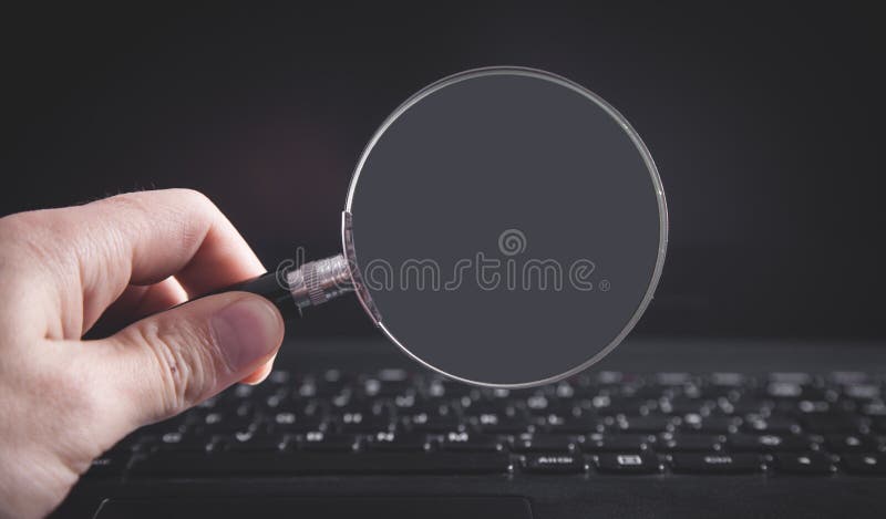Hand Holding Magnifying Glass with Laptop Keyboard. Searching Internet ...