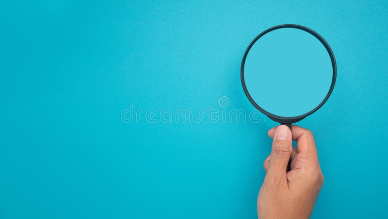 Hand Holding of a Magnifying Glass Over a Blue Background with Space ...