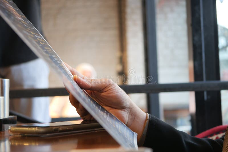 Hand Holding a Menu in a Cozy Restaurant Setting Stock Image - Image of ...