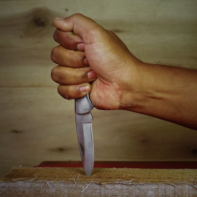 Hand Holding a Metal Knife that Stuck in the Wood Stock Photo - Image ...