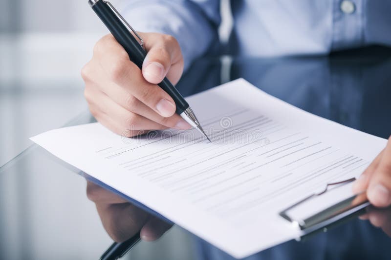 A Hand Holding a Pen is Poised Over a Document, Indicating the Act of ...