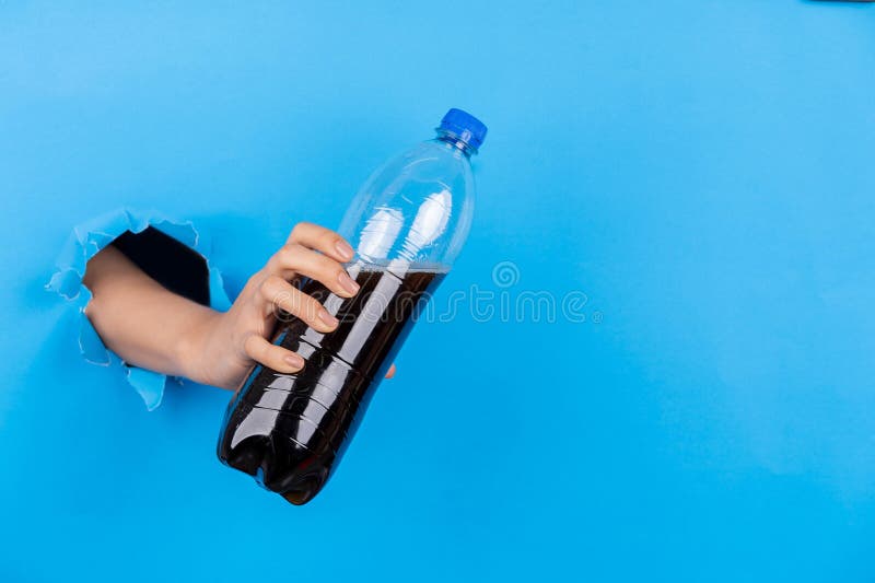 Hand Holding Plastic Bottle through Hole in Blue Paper Stock Photo ...