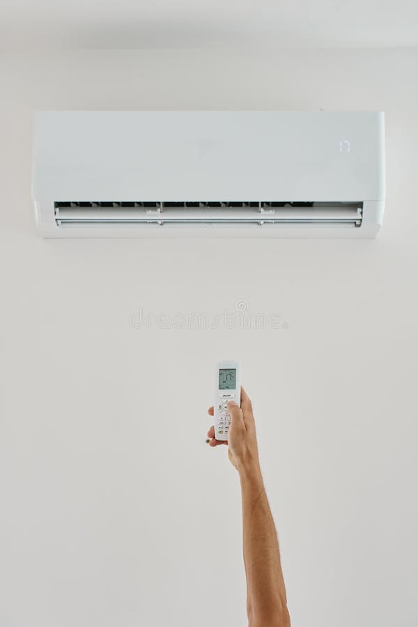Hand Holding Remote Control To Set Temperature on Wall Air Conditioner ...