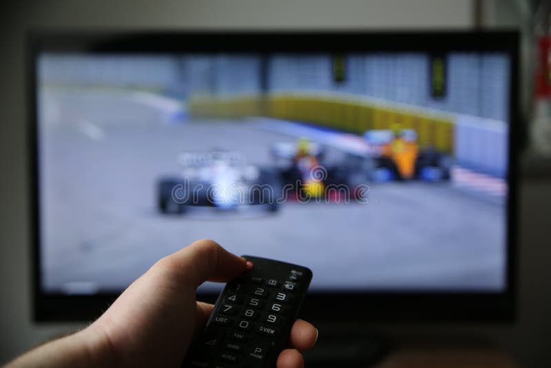 Hand Holding the Remote Controller Against the Blurred TV Screen ...