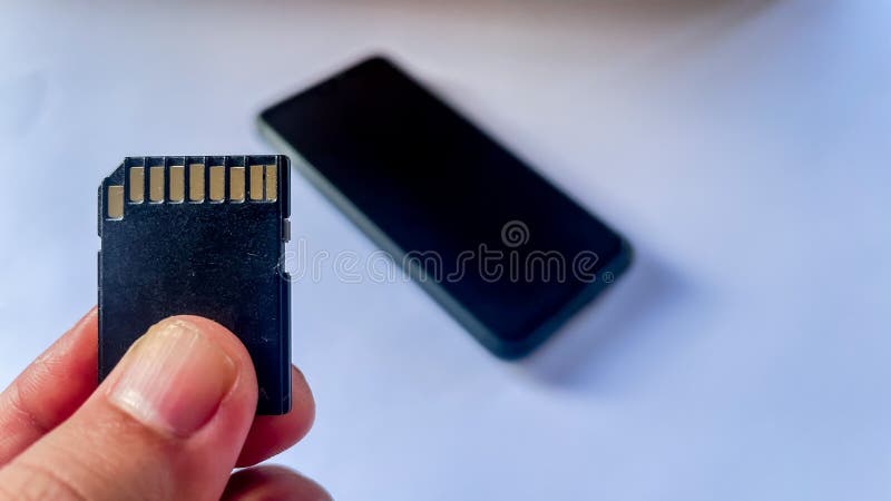 Hand Holding Sdcard on White Background with the Smartphone Blurred on ...